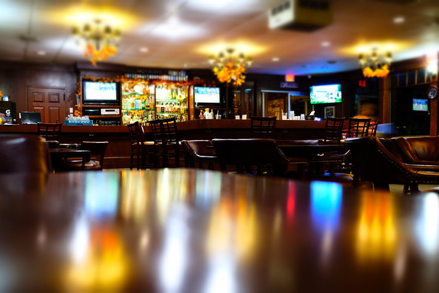 Evening Bar Interior: Warm ambient lighting, leather lounge, and colorful reflections on a polished wooden table